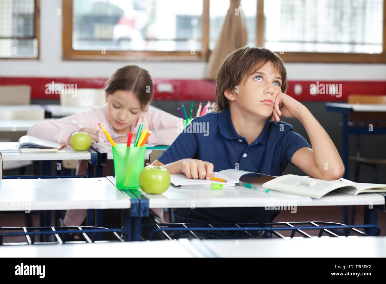 Young Boy Looking Up In Classroom Stock Photo - Alamy