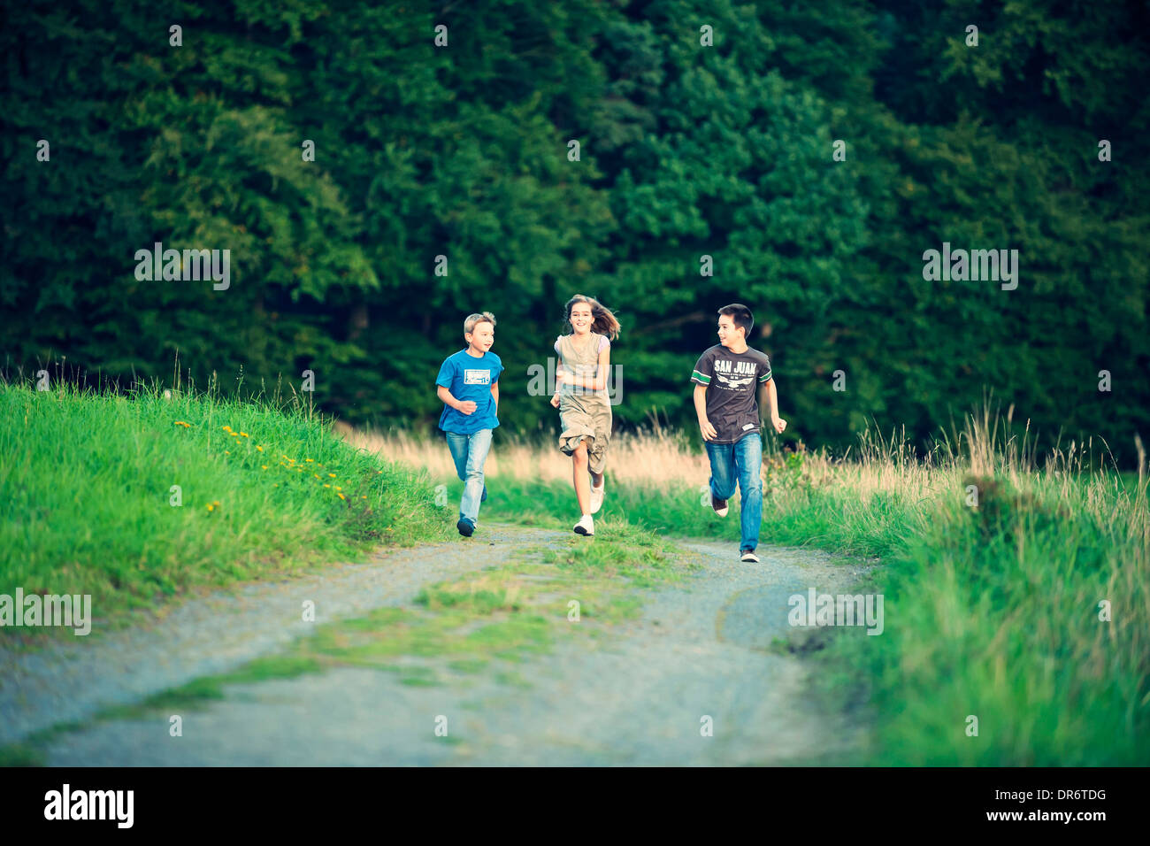 Three siblings running side by side on a path Stock Photo - Alamy