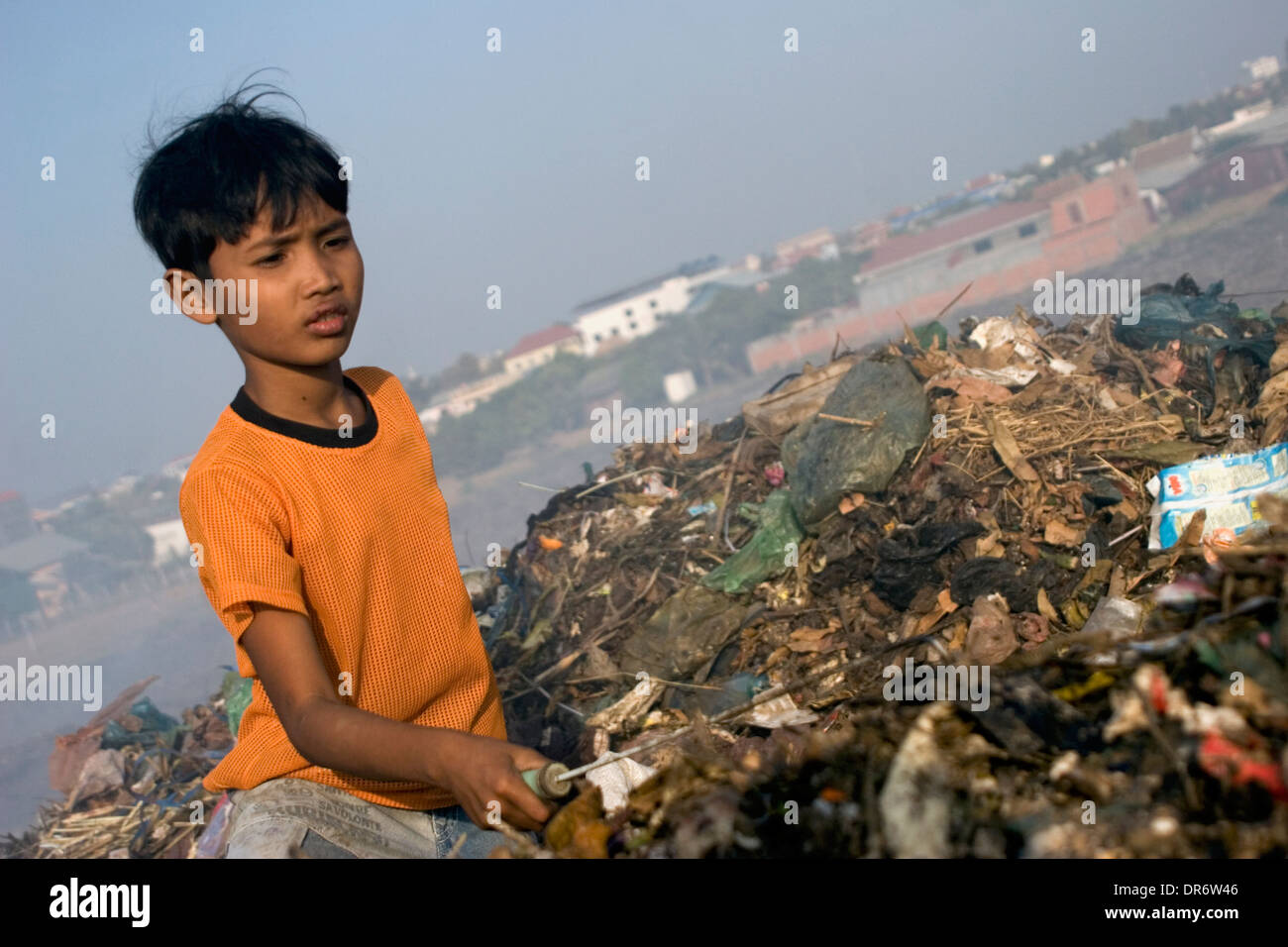 A young child laborer boy looks through garbage for plastic bags at the ...