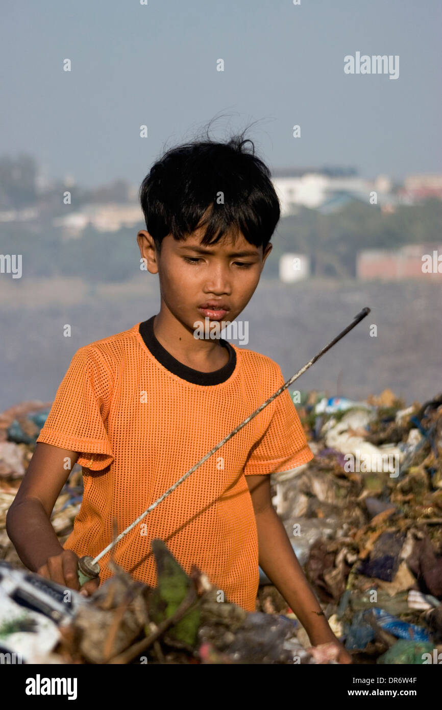A young child laborer boy looks through garbage for plastic bags at the ...
