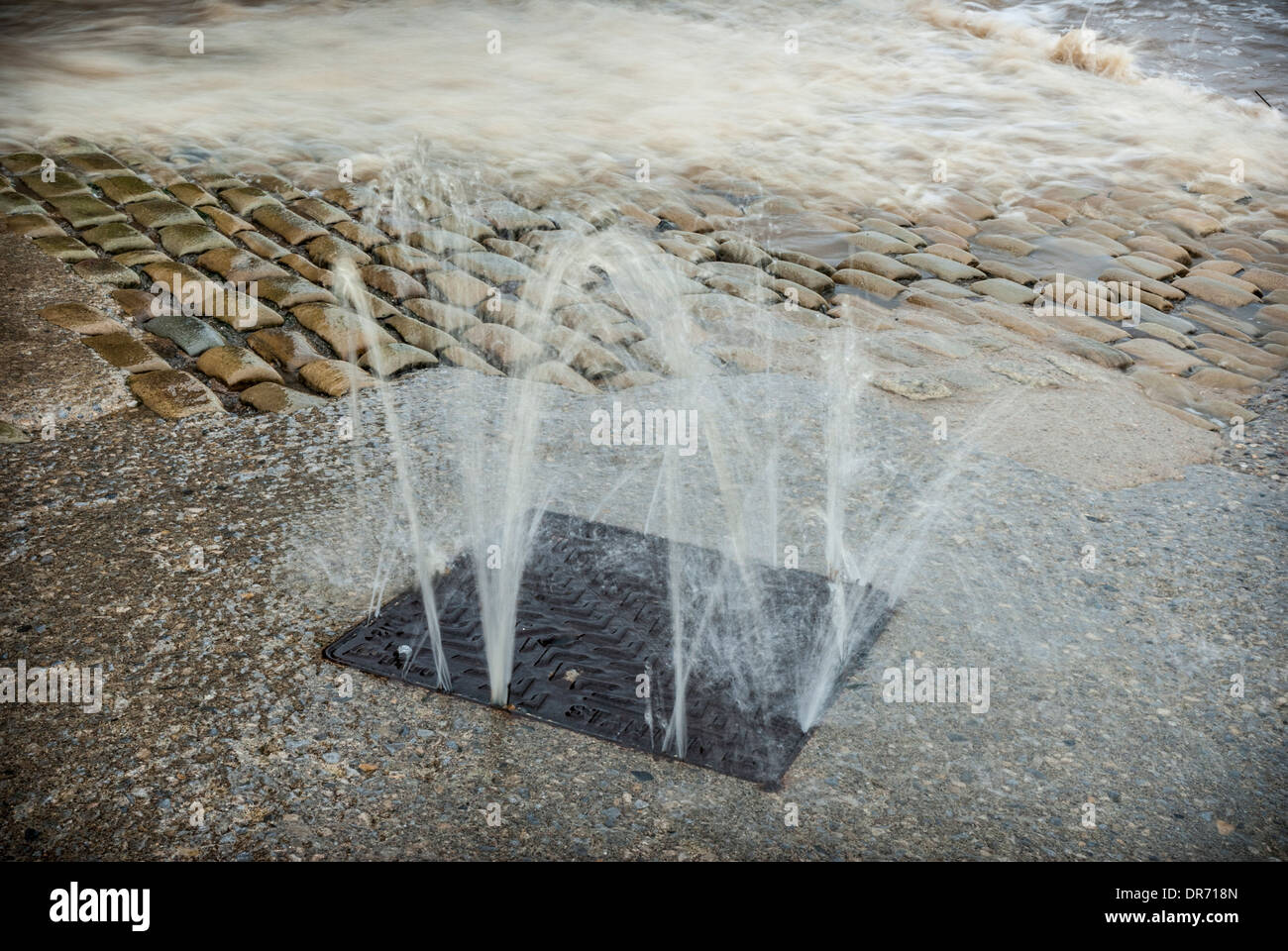 Water bursting from a drain into the road during severe floods Stock ...