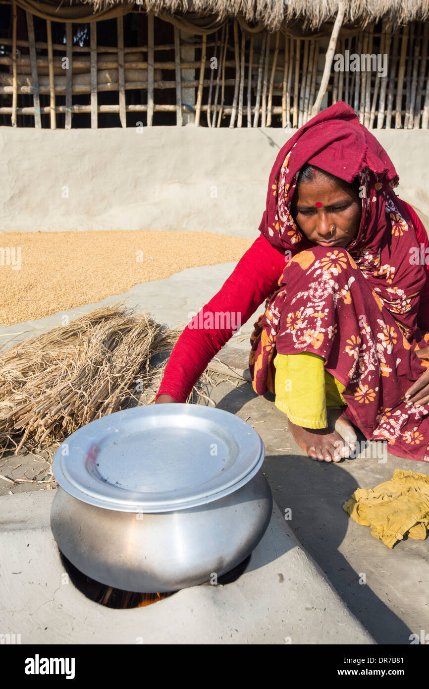 A woman subsistence farmer cooking on a traditional clay oven, using ...