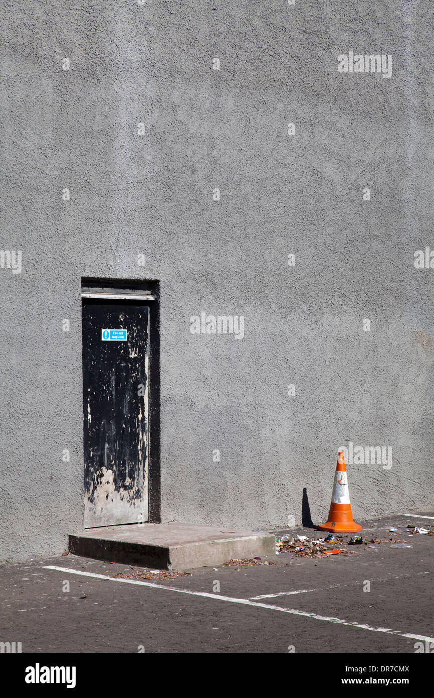 Exit door in a large rendered grey wall with traffic Stock Photo - Alamy