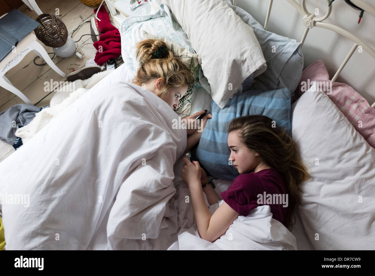 Two 14 15 year old teenage girls in bed, not talking, texting on their ...