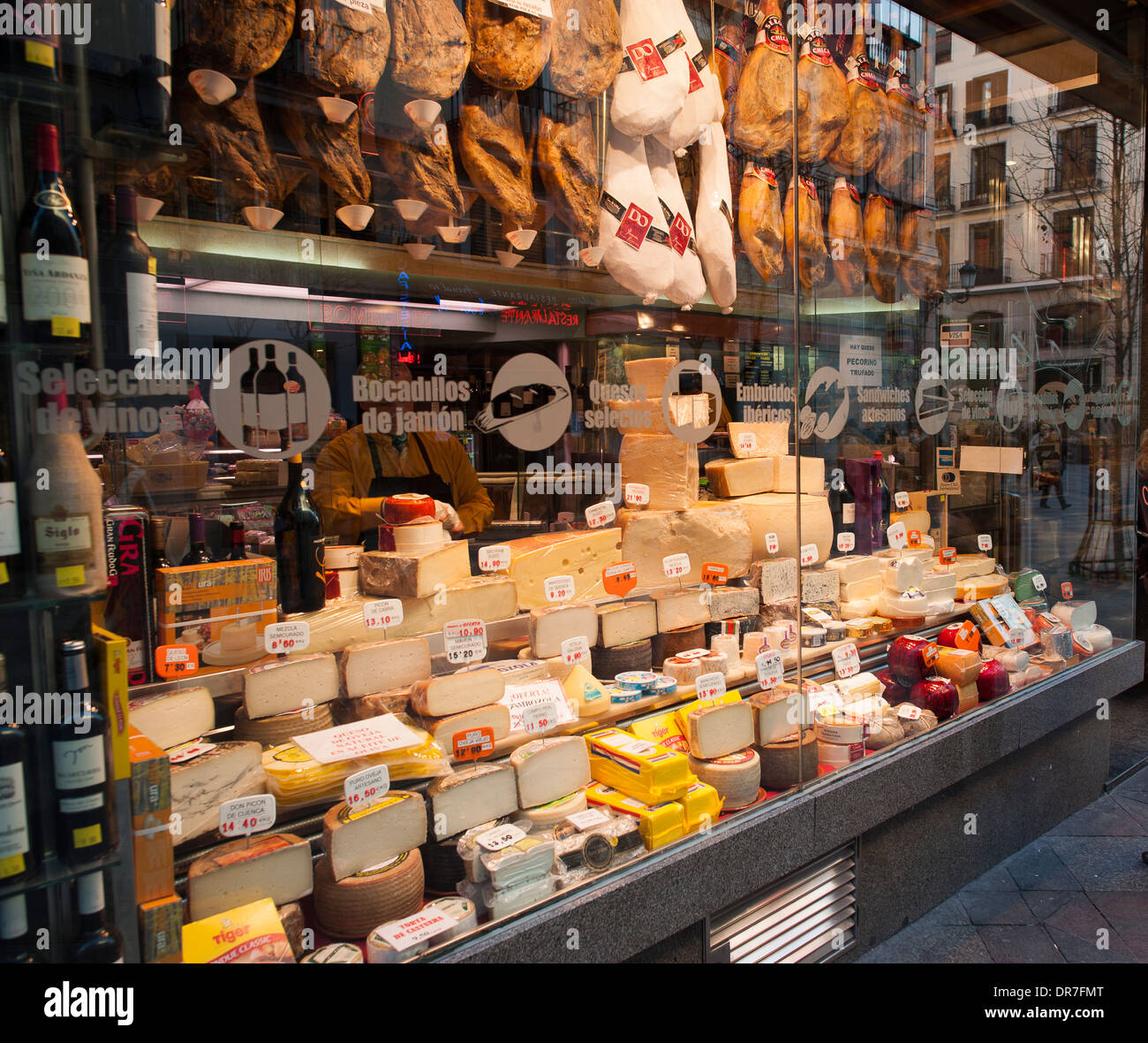 Delicatessen window display showing cheeses, hams and bottles of wine ...