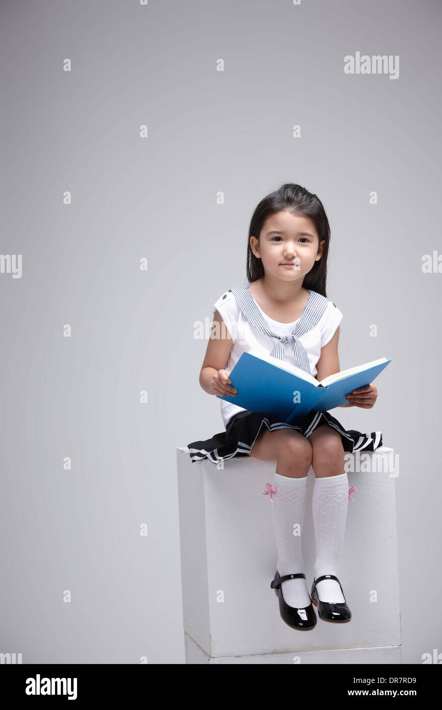 a girl sitting on a box reading a book Stock Photo - Alamy