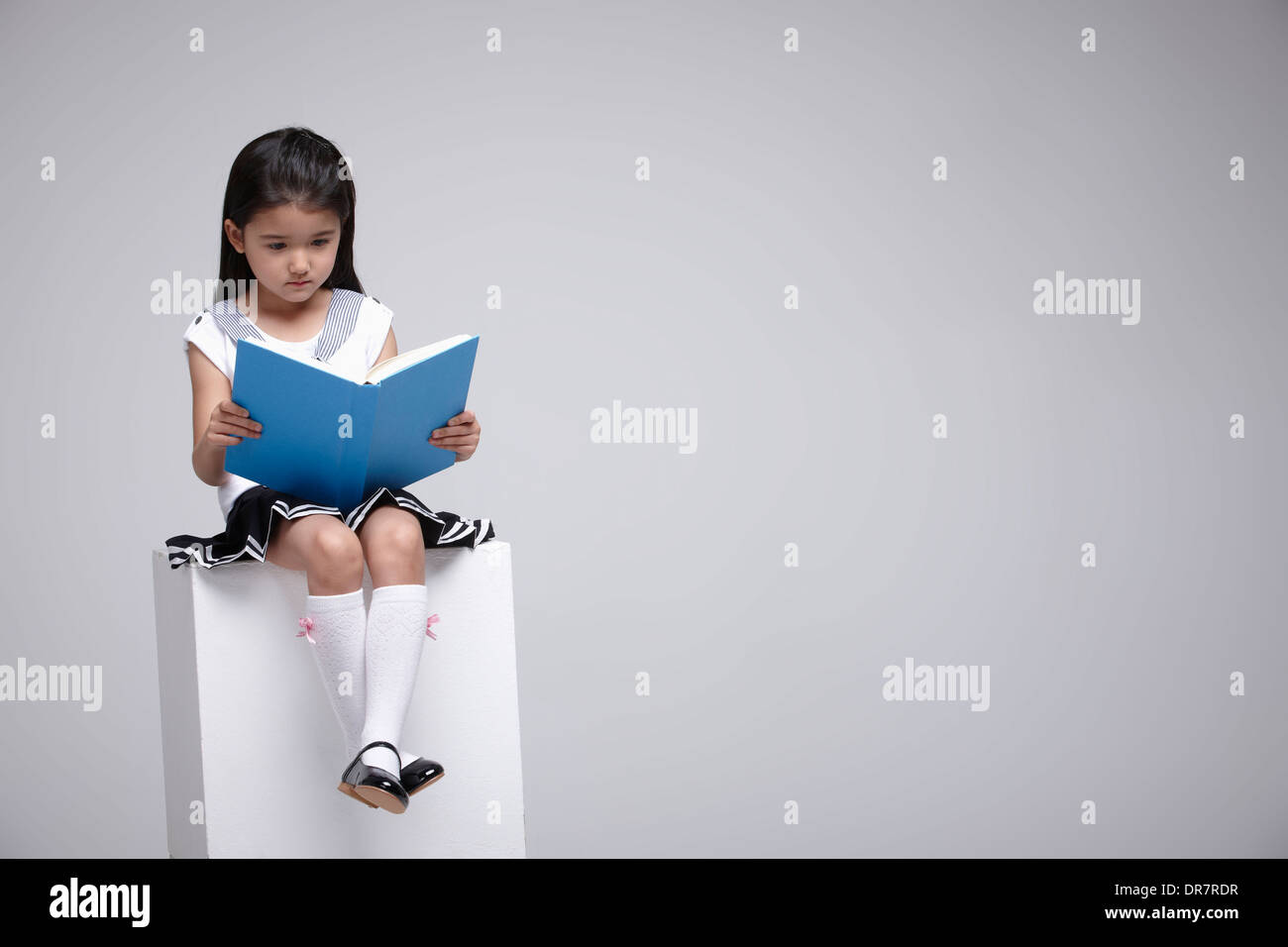 a girl sitting on a box reading a book Stock Photo - Alamy