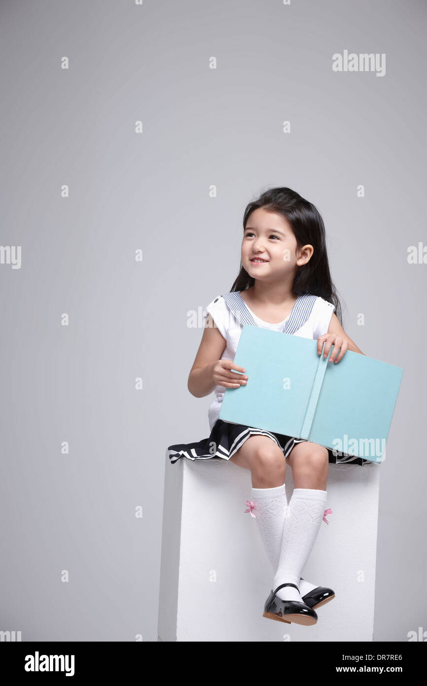 a girl sitting on a box with a book Stock Photo - Alamy