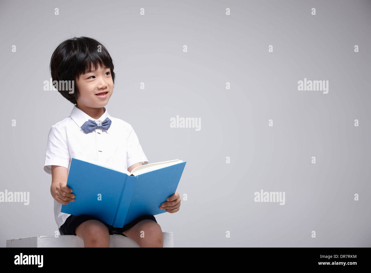 a boy sitting on a box reading a book Stock Photo - Alamy