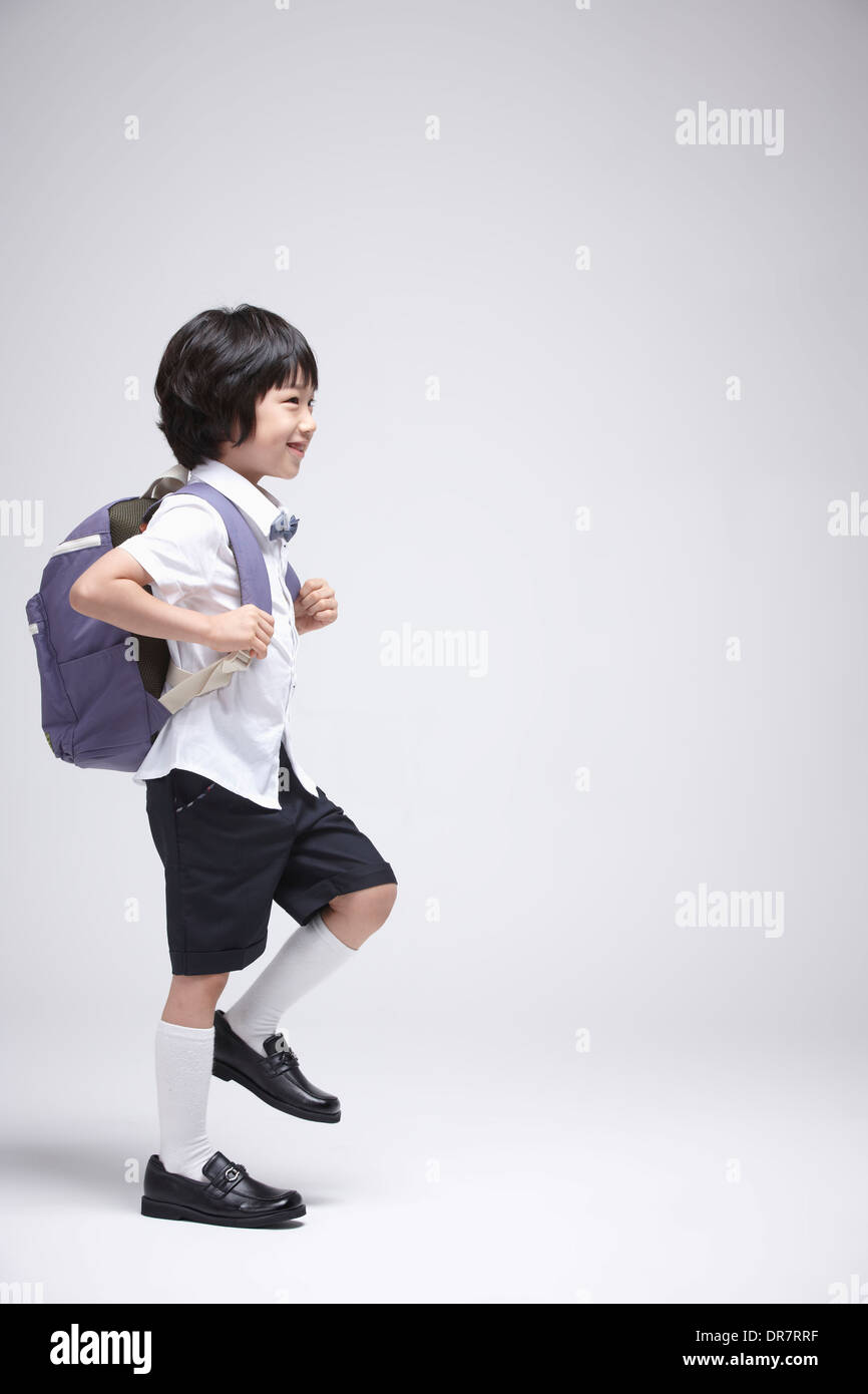 a boy wearing a school bag walking in white background Stock Photo - Alamy