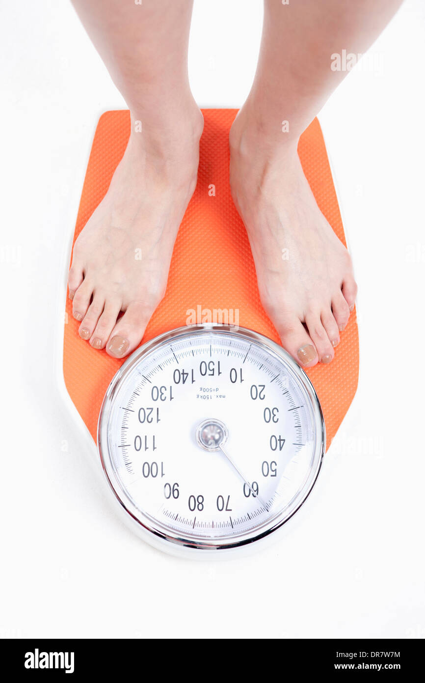 a woman measuring herself on weighing scale Stock Photo - Alamy