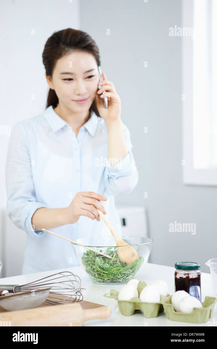 a woman talking on the phone while cooking Stock Photo - Alamy