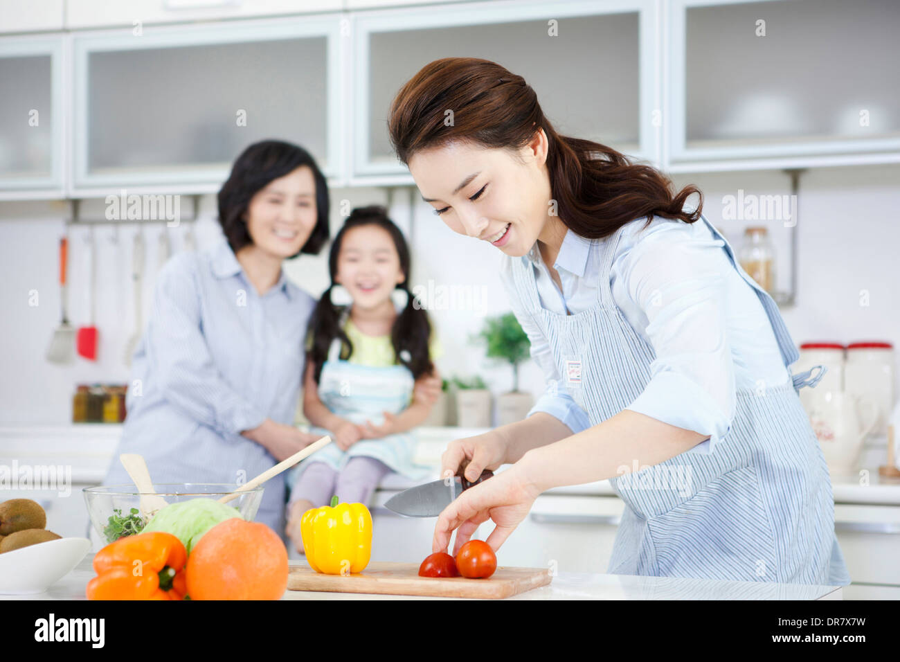 a mother and a daughter watching a woman cooking Stock Photo - Alamy