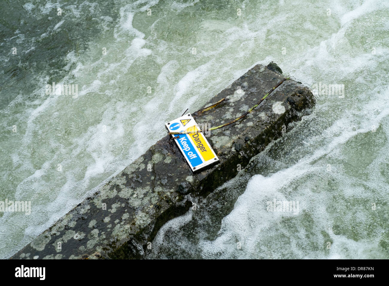 Small danger keep off sign attached to concrete post in fast flowing ...