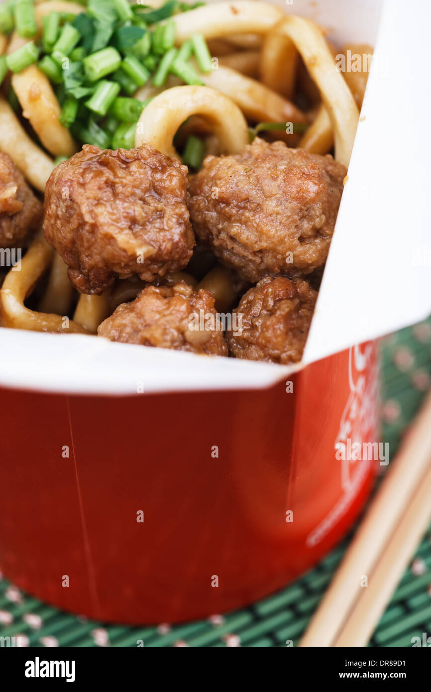 a red takeout box with beef meatballs and noodles. Shallow depth of ...