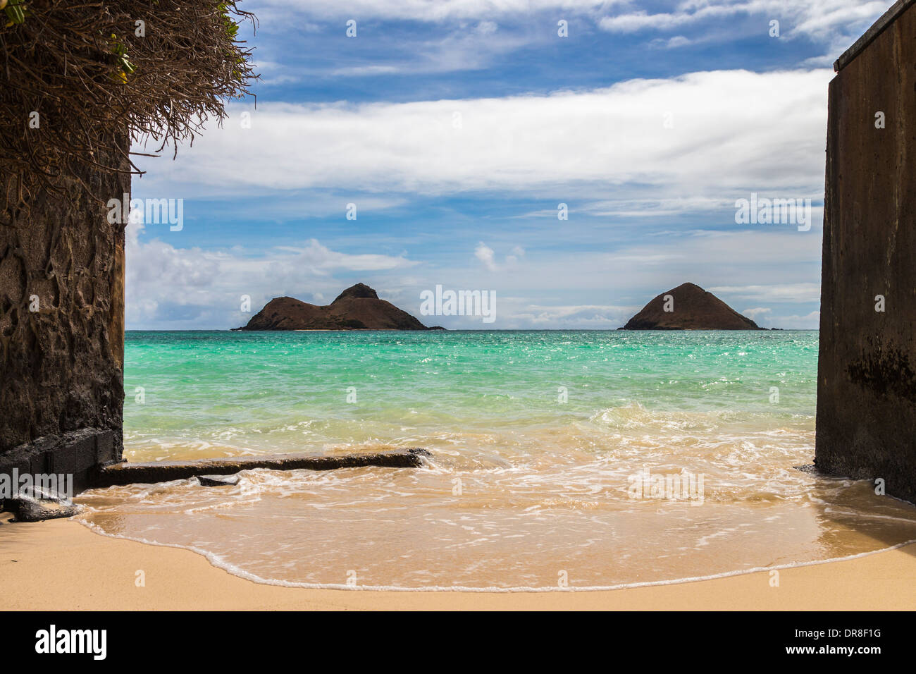 A narrow beach opening with a view of Na Mokulua Islands, also known as ...