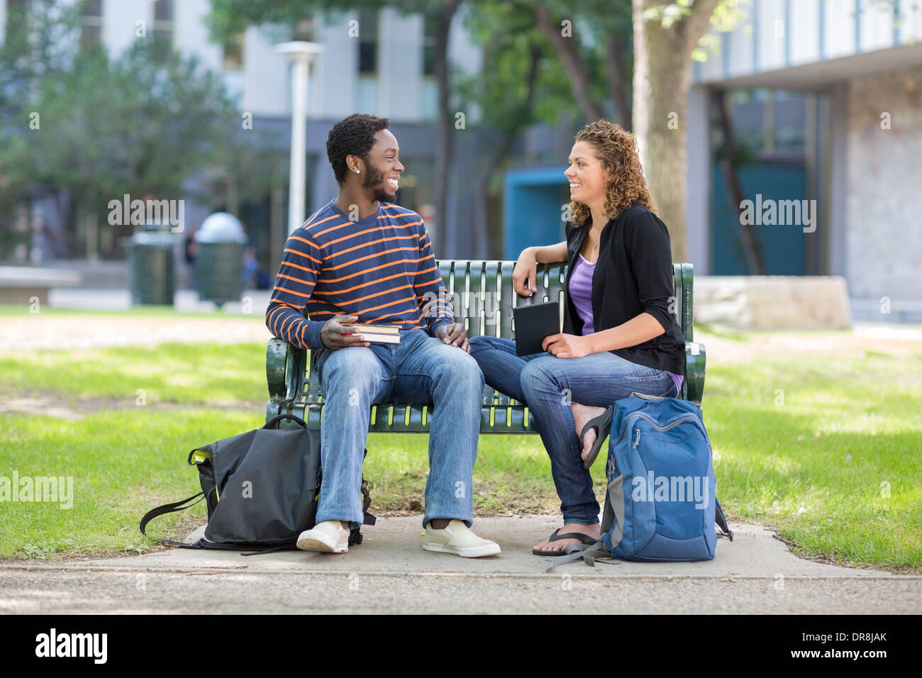 Students Sitting On Bench At University Campus Stock Photo - Alamy