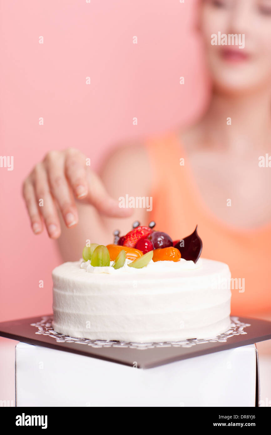 a woman about to grab a cake in front of her Stock Photo - Alamy