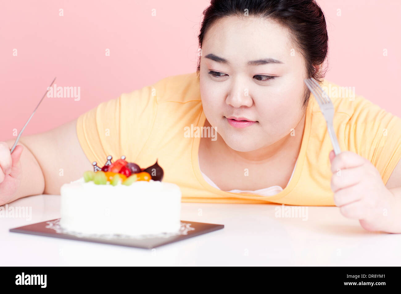 a chubby woman with a cake in front of her Stock Photo - Alamy