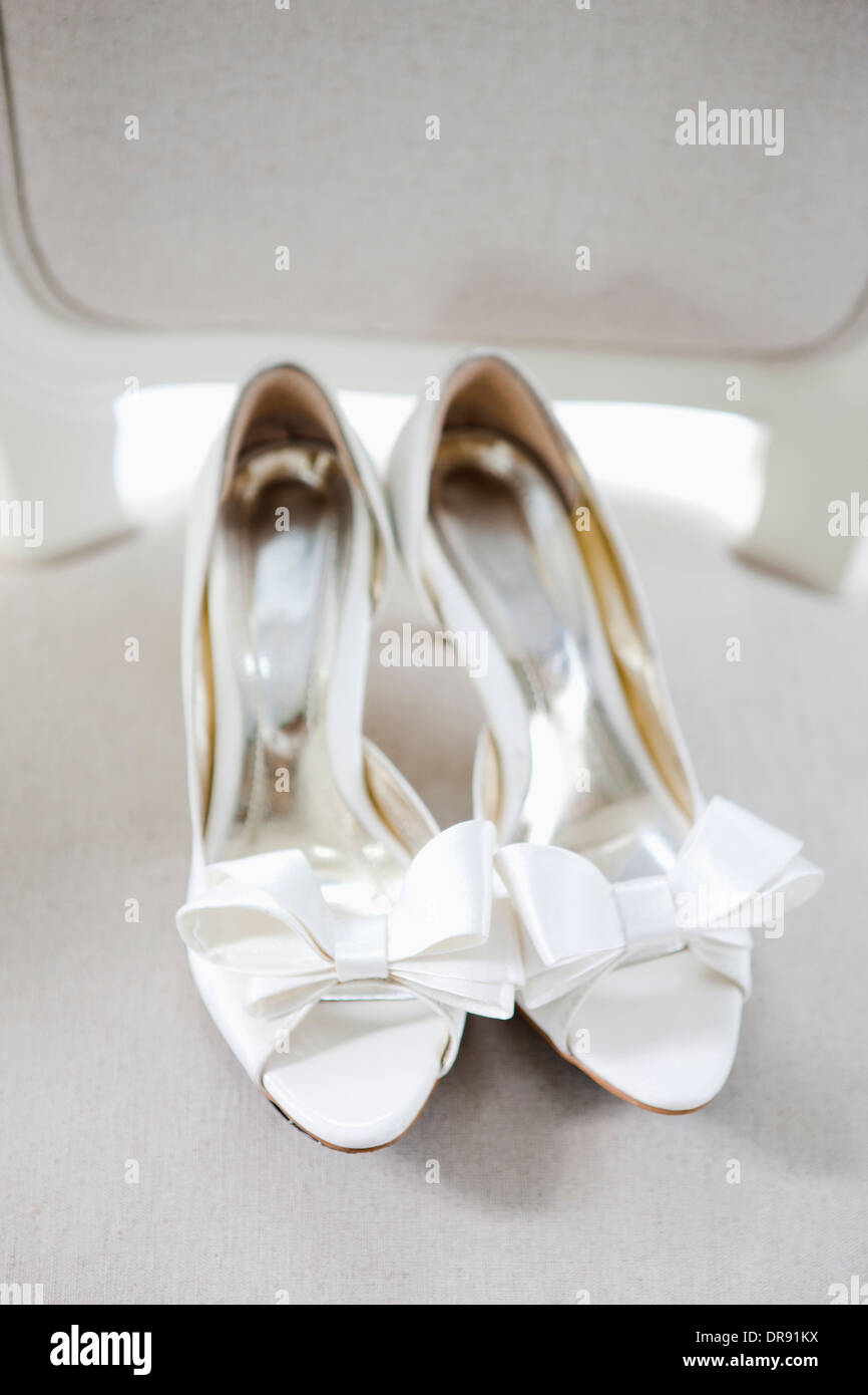 a pair of white heels with ribbon on a chair Stock Photo - Alamy