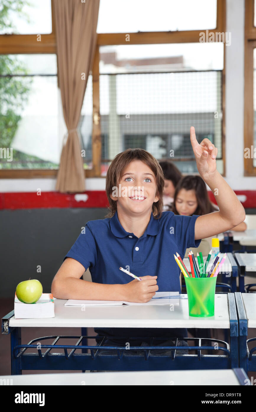 Boy pupil raising hand in class hi-res stock photography and images - Alamy