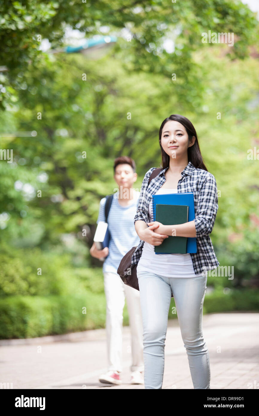 a university student walking in the campus holding books Stock Photo ...