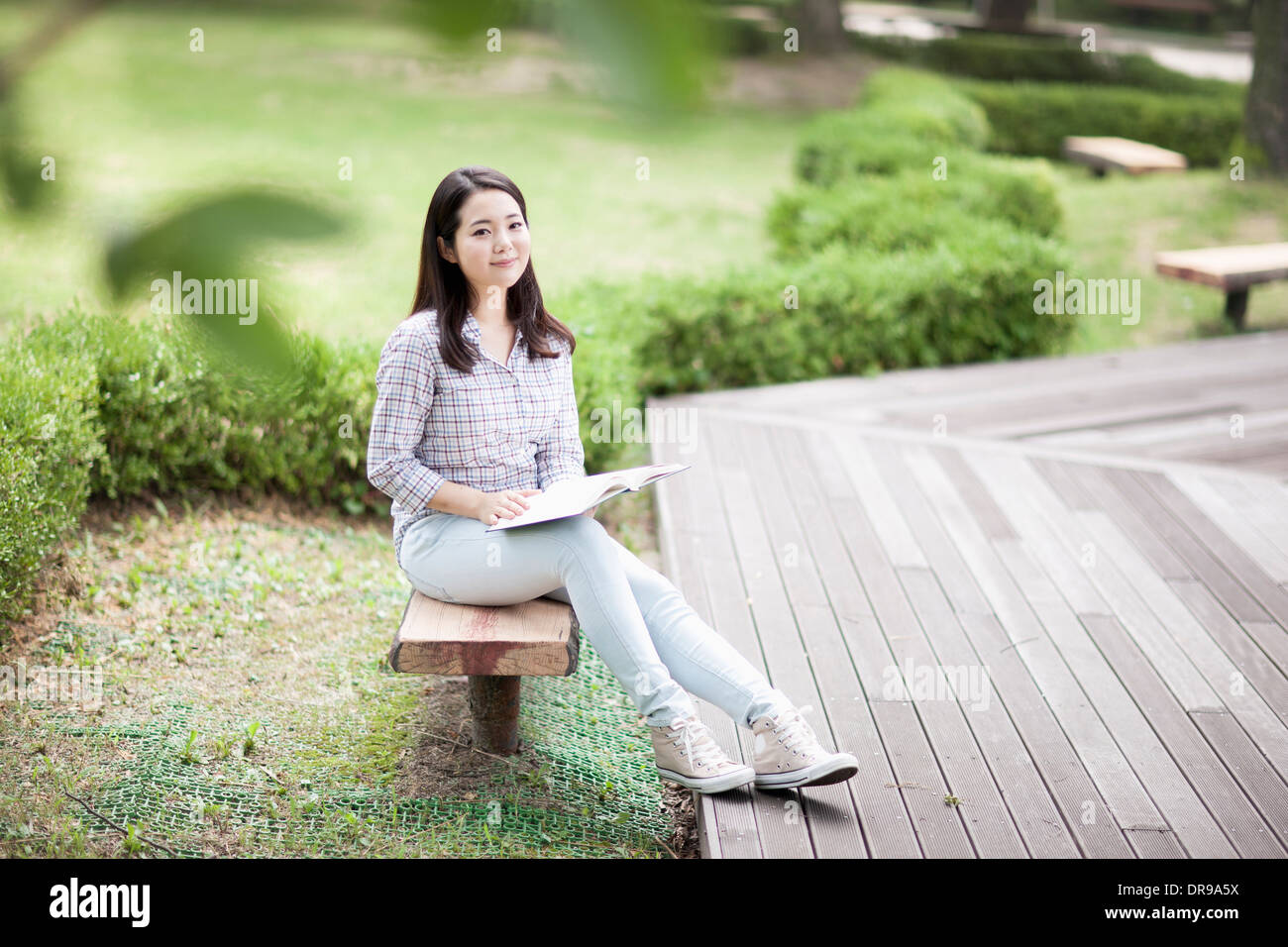 a woman sitting on a bench reading a book Stock Photo - Alamy