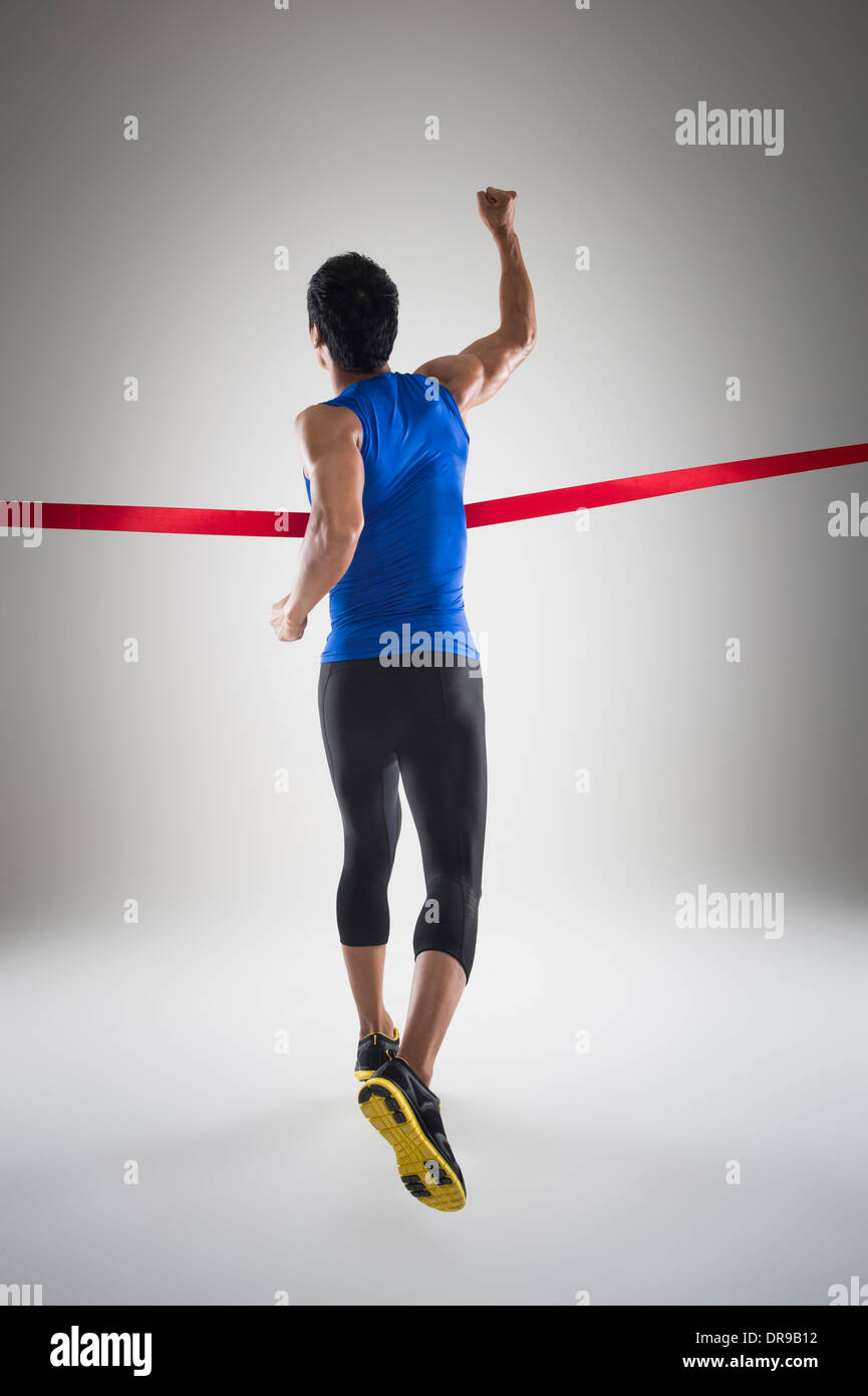 back shot of a fit man in blue shirt running to a finishing line Stock ...