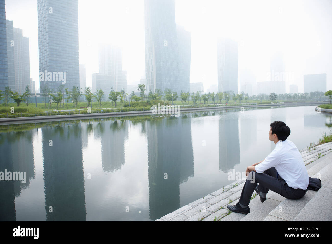 a business man sitting next to a river Stock Photo - Alamy
