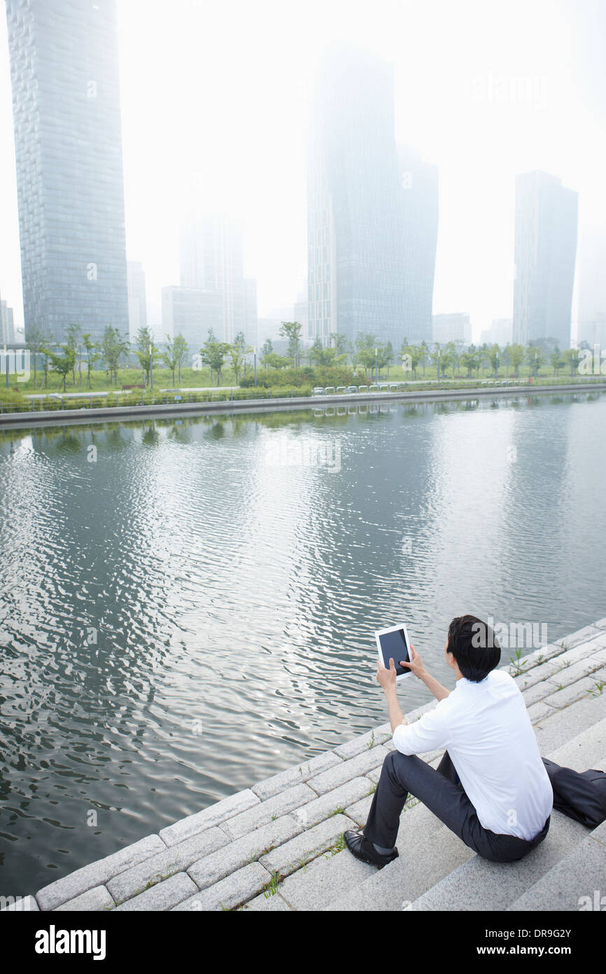 a business man sitting next to a river Stock Photo - Alamy
