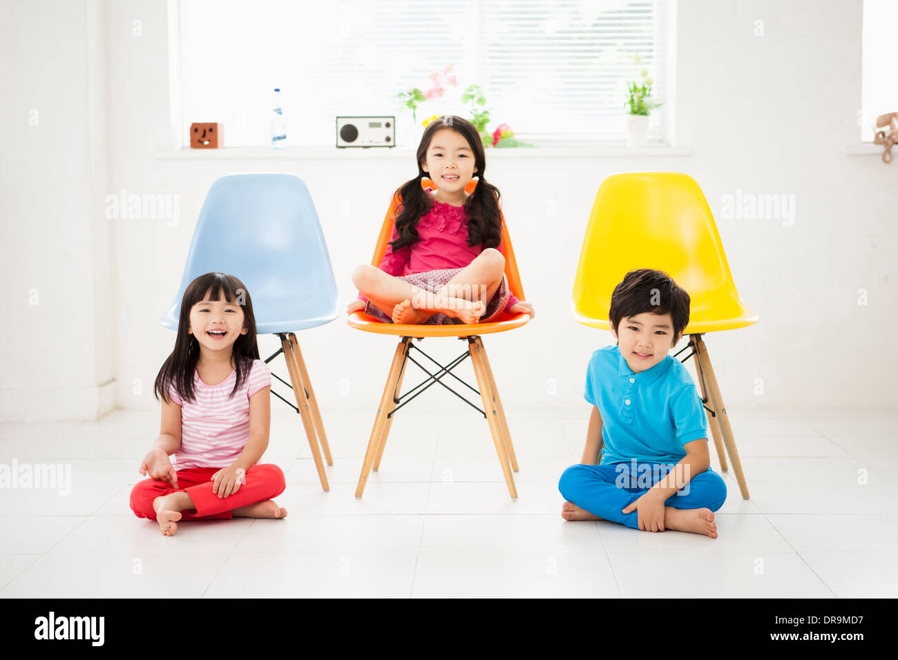 kids sitting next to chairs Stock Photo - Alamy