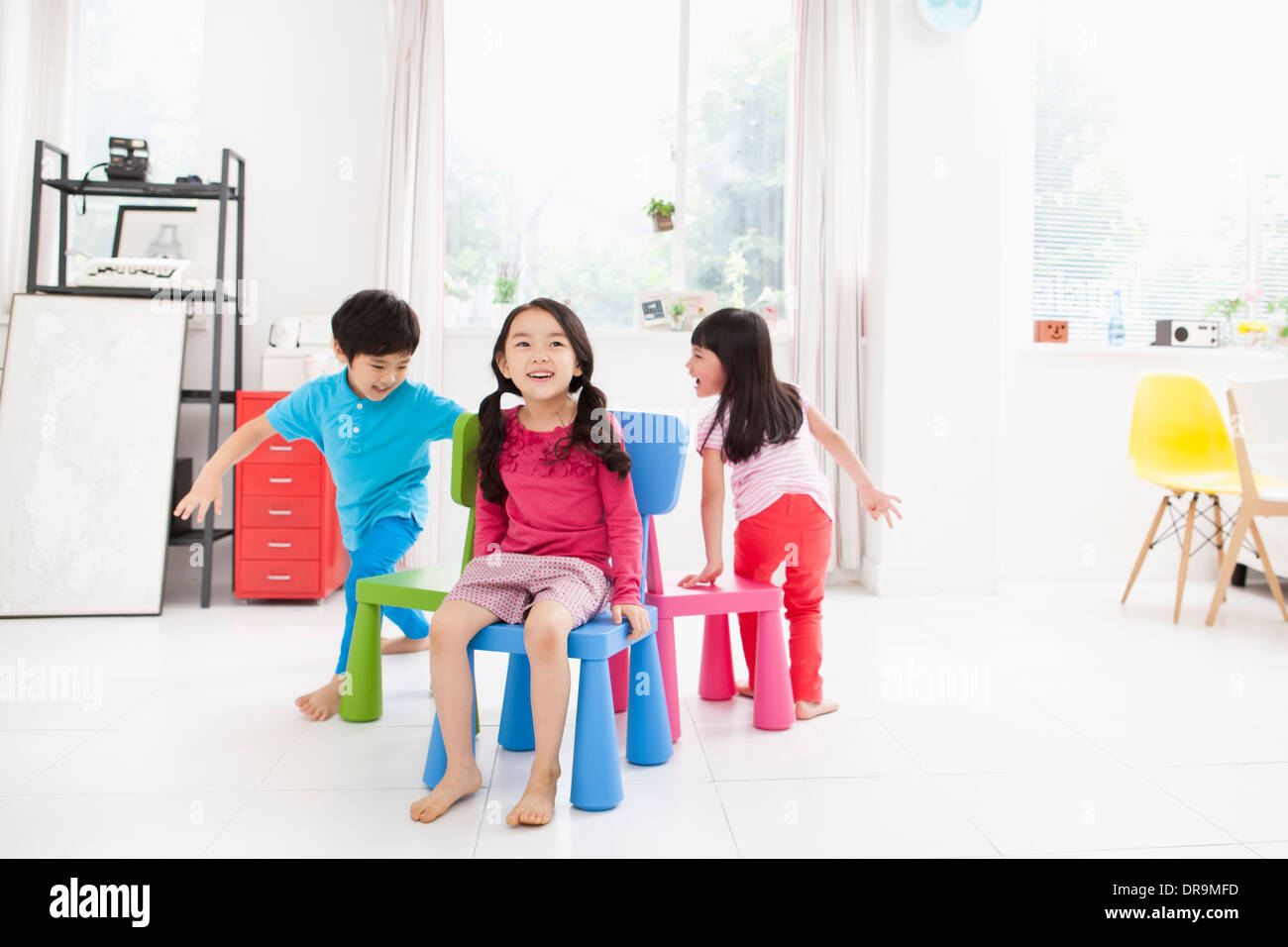 kids playing with different color chairs Stock Photo - Alamy