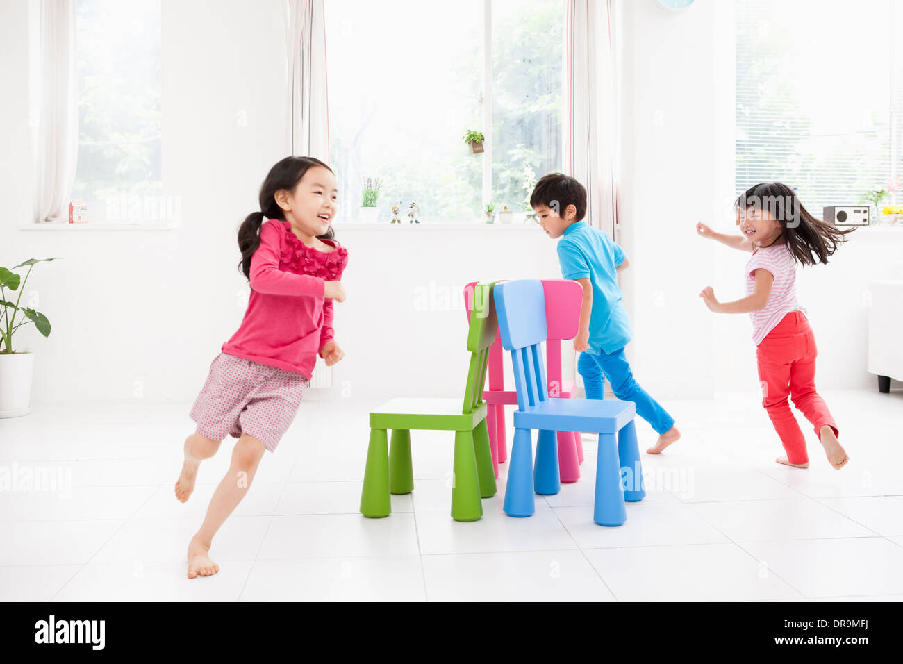 kids playing with different color chairs Stock Photo - Alamy