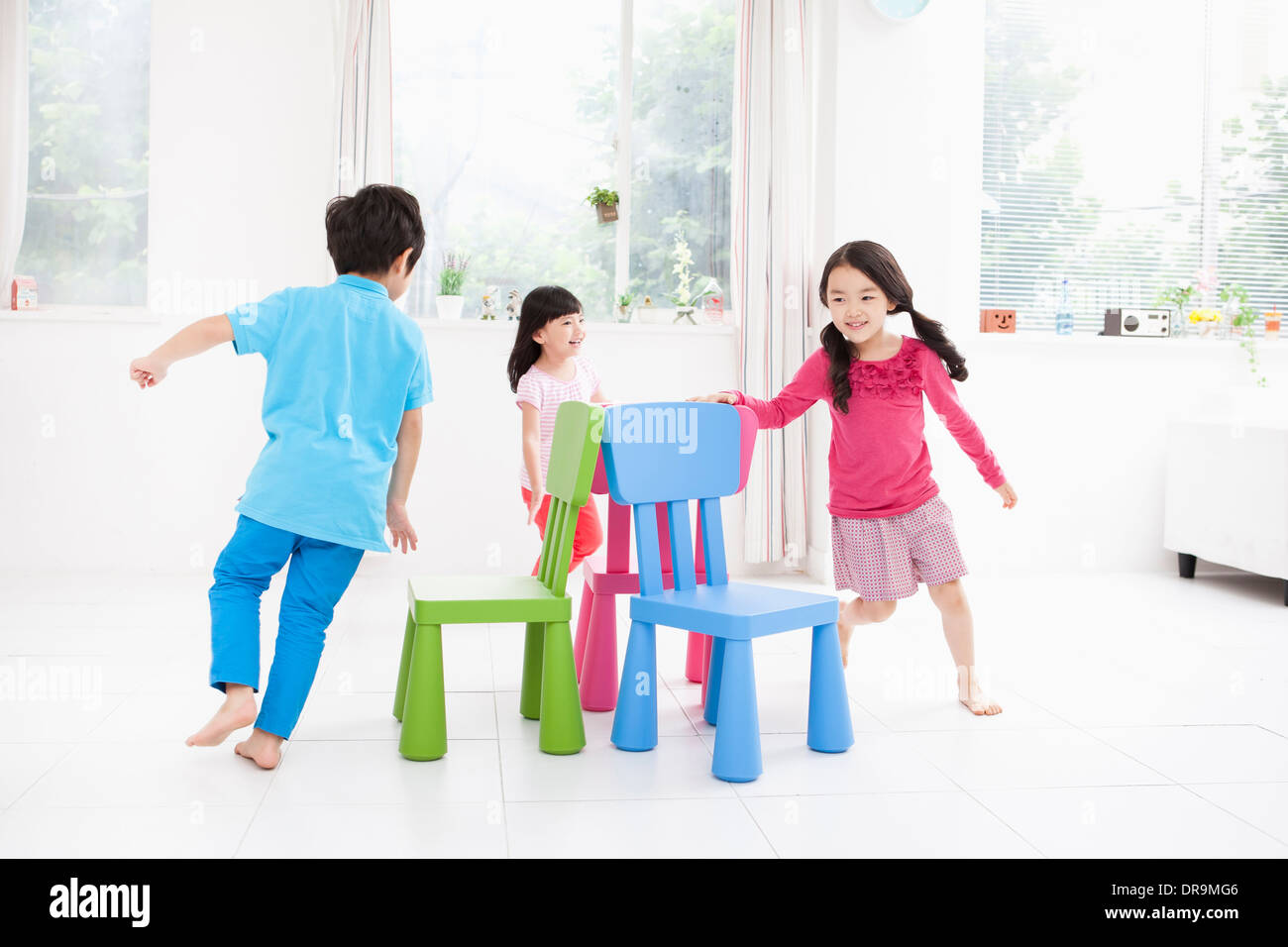 kids playing with different color chairs Stock Photo - Alamy