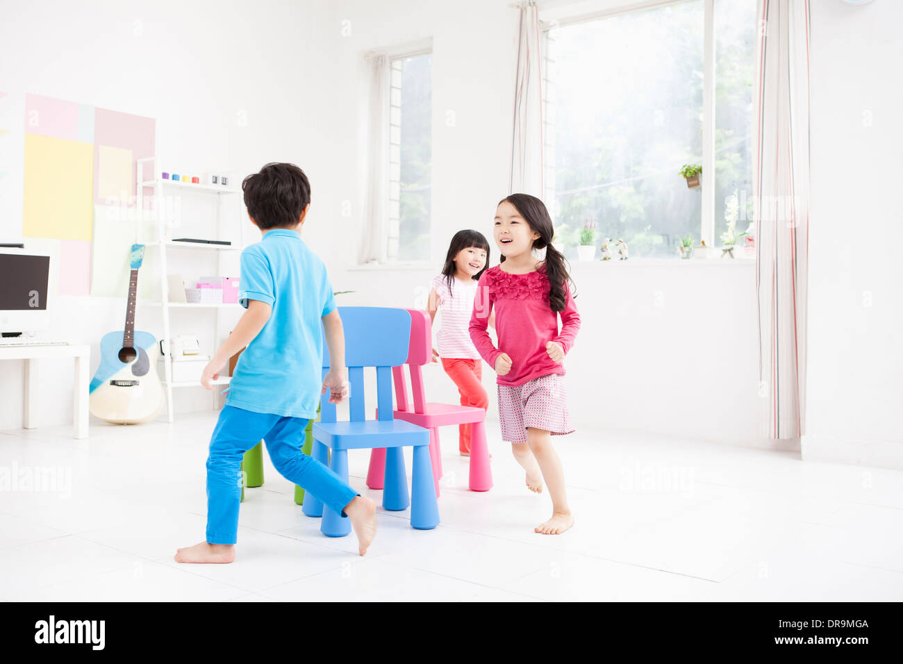 kids playing with different color chairs Stock Photo - Alamy