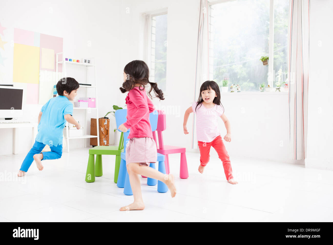 kids playing with different color chairs Stock Photo - Alamy