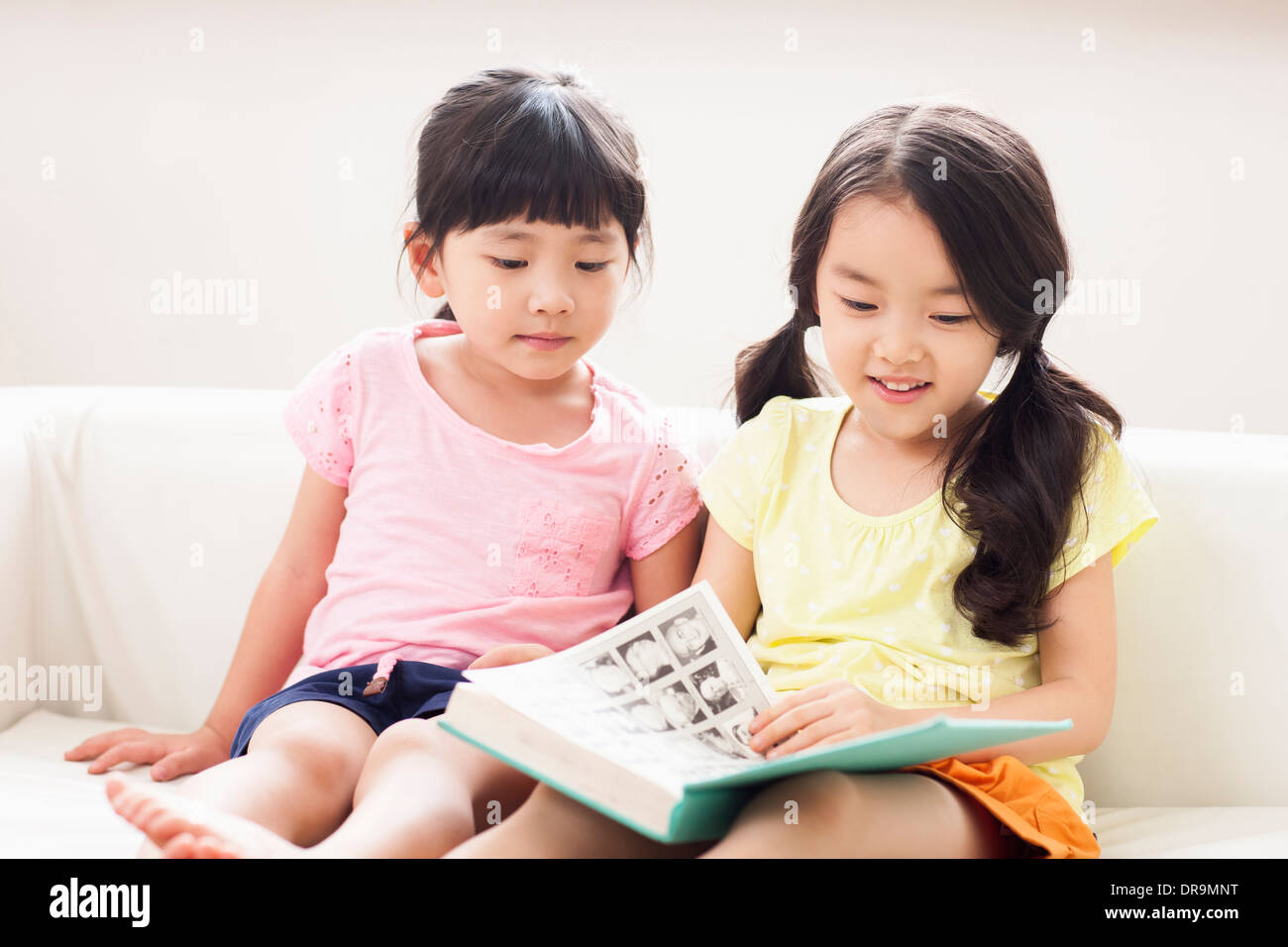 two girls reading a book Stock Photo - Alamy