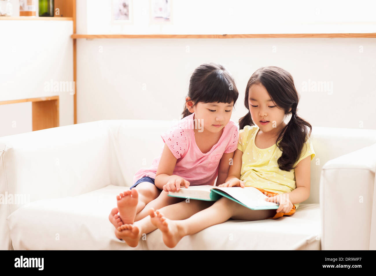 two girls reading a book Stock Photo - Alamy