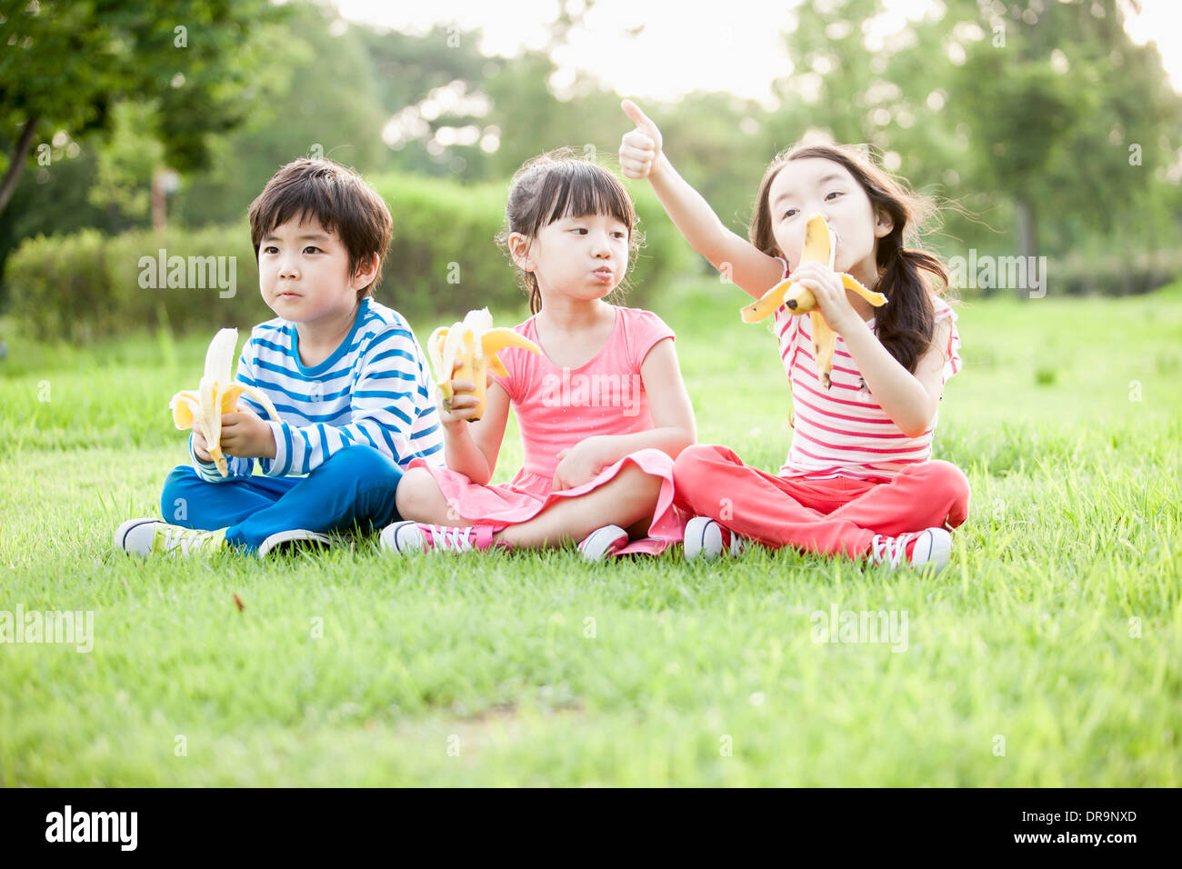 kids sitting on the grass eating bananas Stock Photo - Alamy