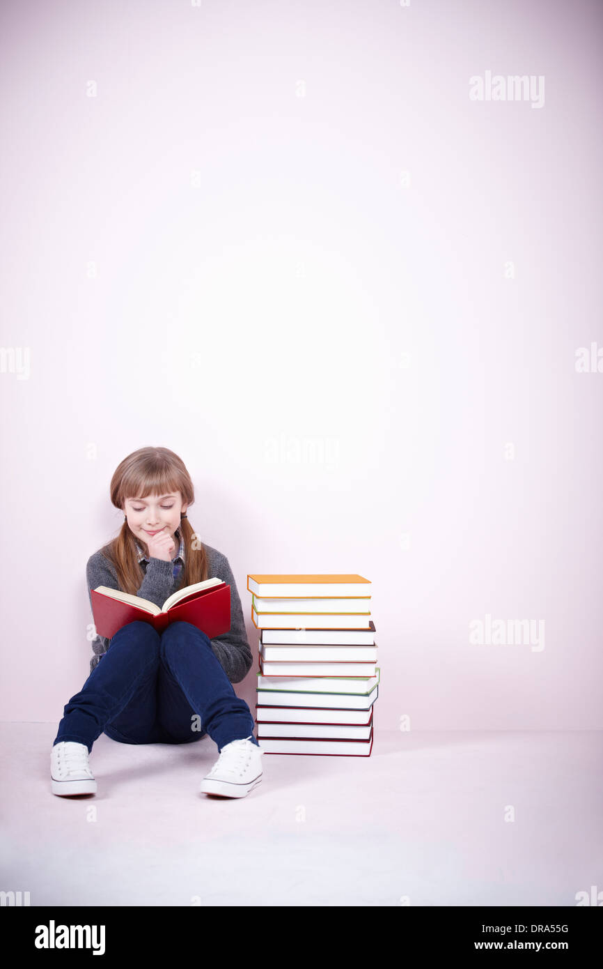 Girl sitting on pile of books reading hi-res stock photography and ...