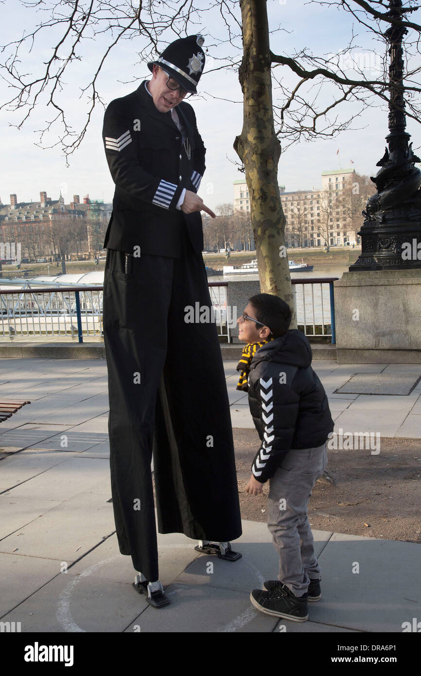 Street performer dressed as a tall policeman. He jokes with tourists ...