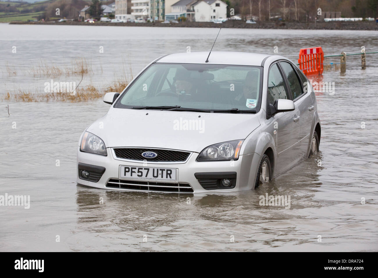 A motorist travels through flood waters on the road at Storth on the ...