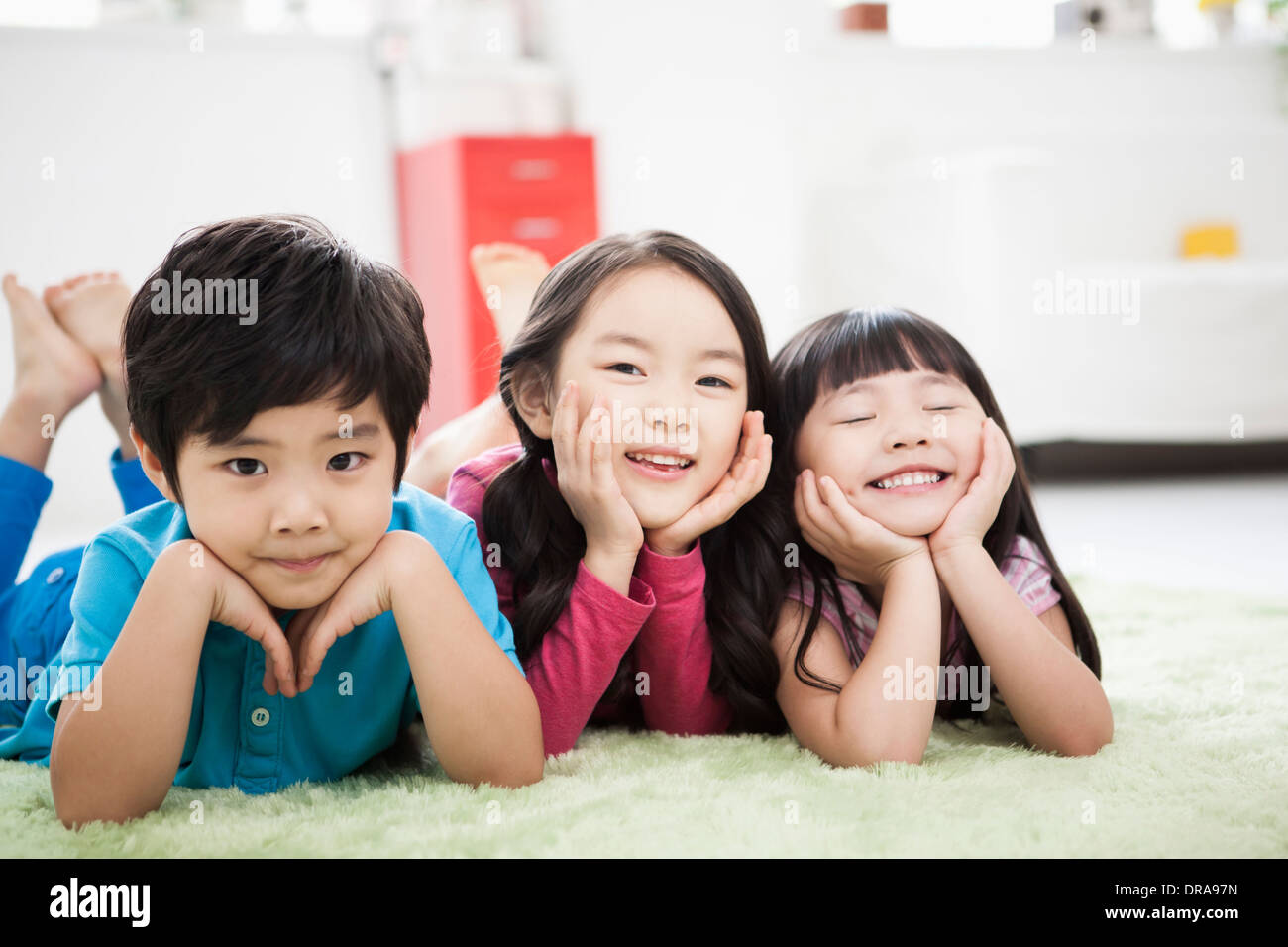 kids lying in the floor carpet with hands under their chin Stock Photo ...
