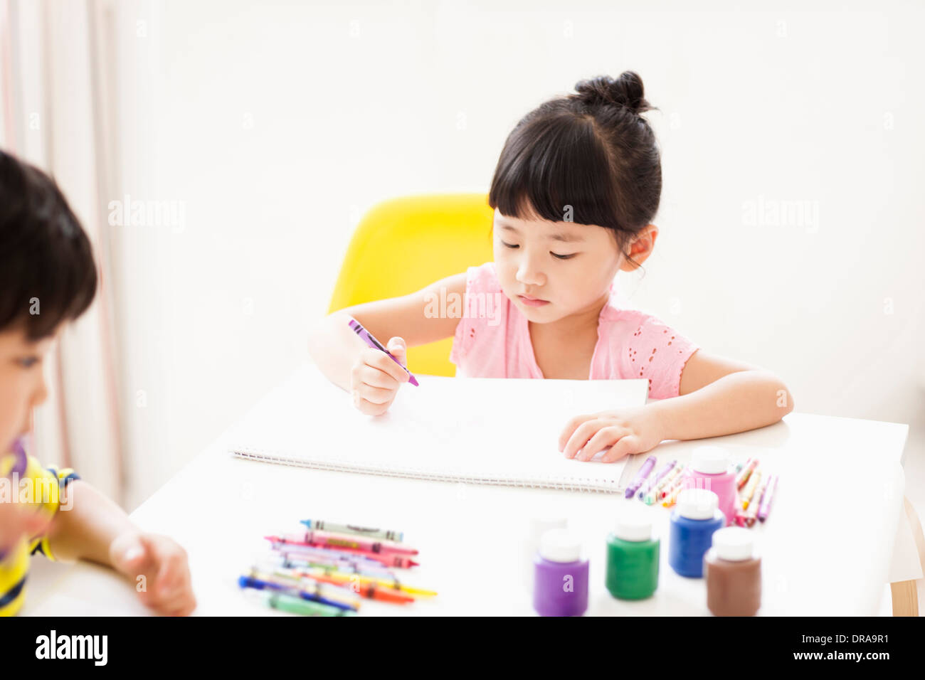 a girl drawing on a sketch book with crayon Stock Photo - Alamy