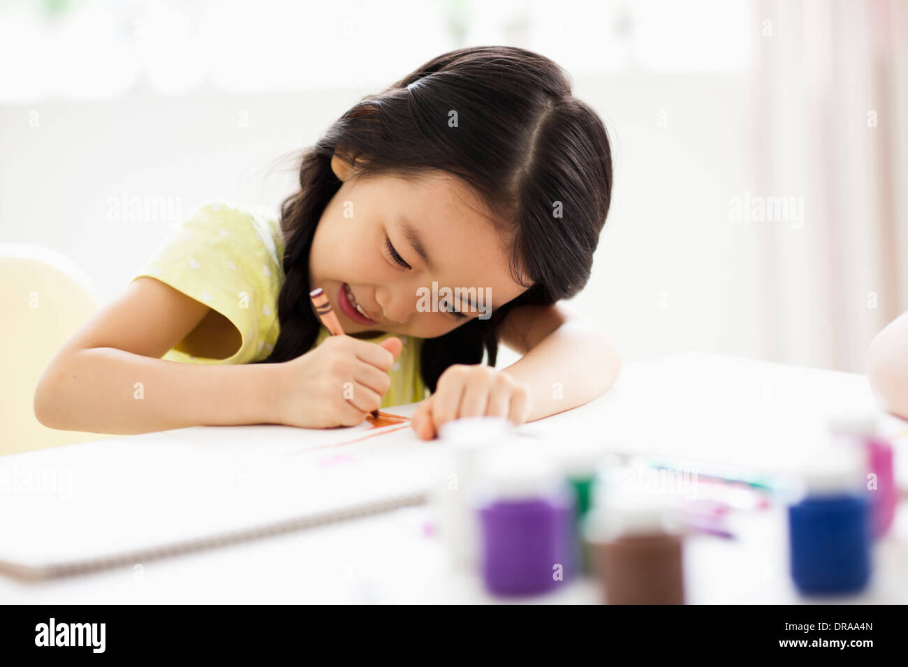a girl drawing on a sketch book with crayon Stock Photo - Alamy