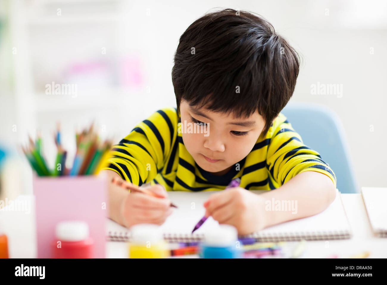 a boy drawing on a sketch book with crayon Stock Photo - Alamy