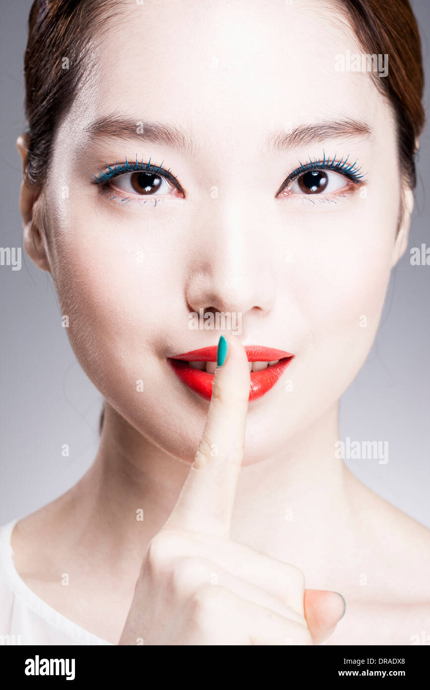 close up shot of a woman with a finger in her red lips Stock Photo - Alamy