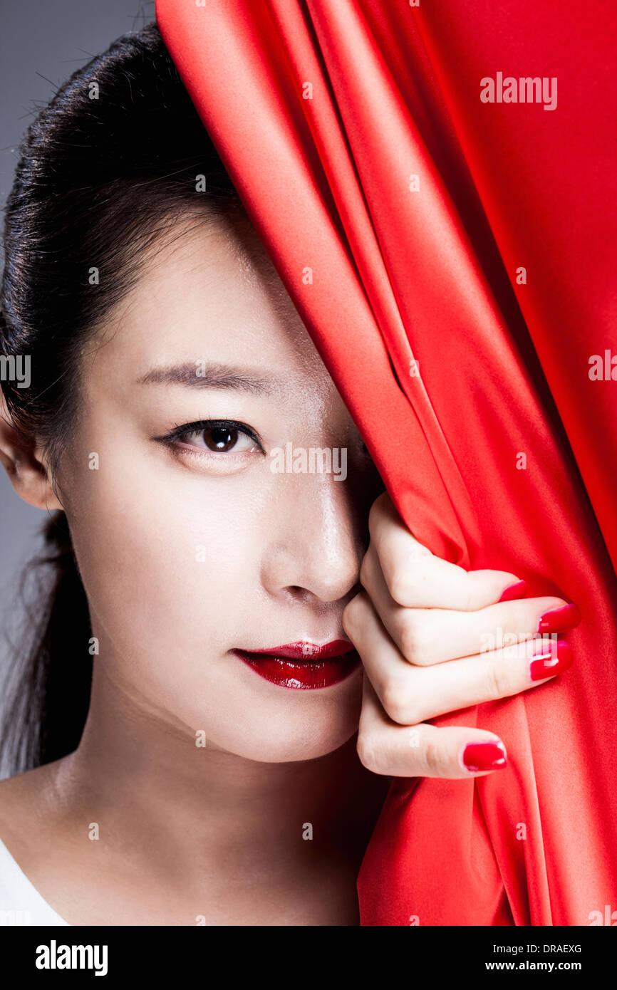 a woman looking at camera behind a red curtain Stock Photo - Alamy