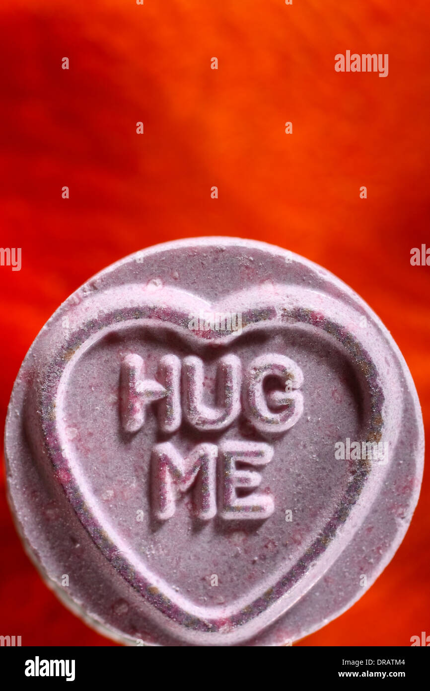 Love heart sweets with hug me message on artificial rose petals Stock ...