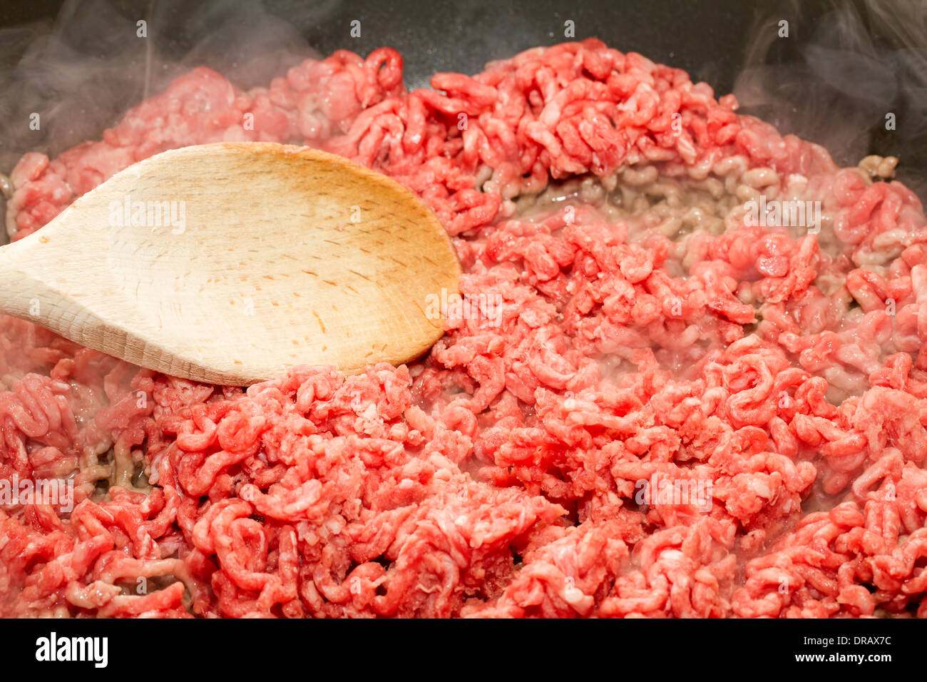 Raw mince starting to brown in pan with wooden spoon Stock Photo - Alamy